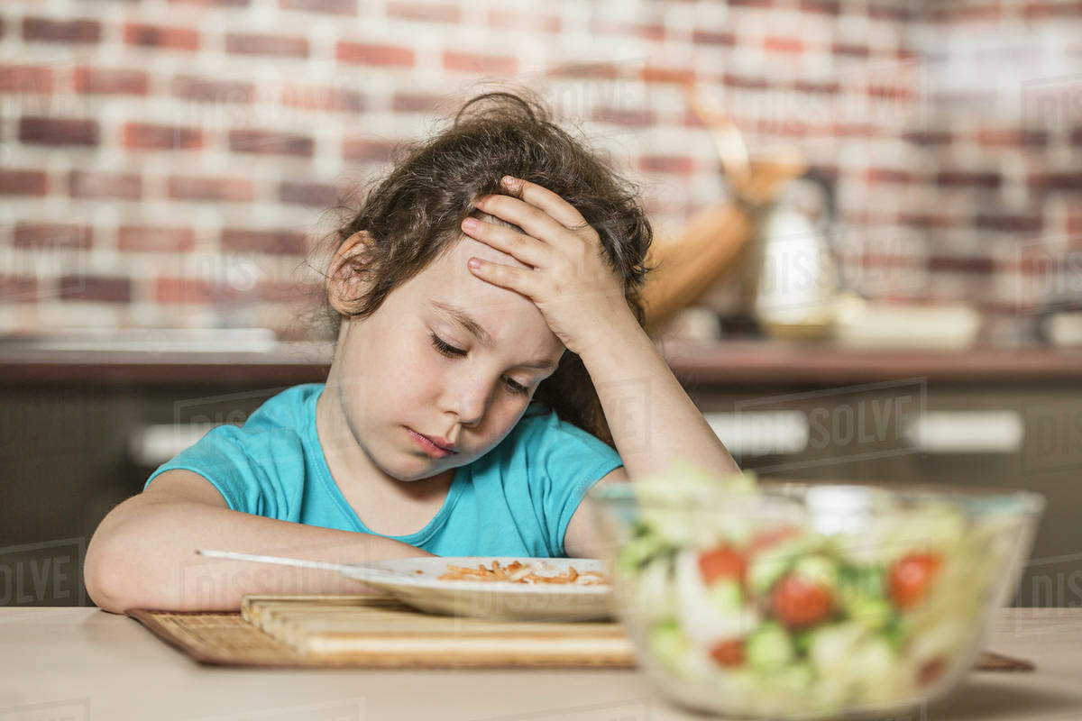 Sad girl with head in hand while having breakfast at table - Stock ...