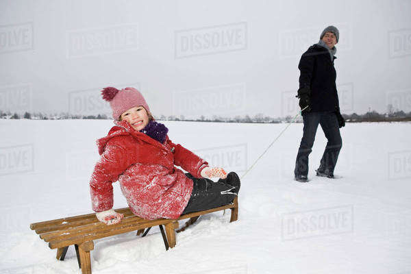 A man pulling a sled daughter on it - Stock Photo - Dissolve