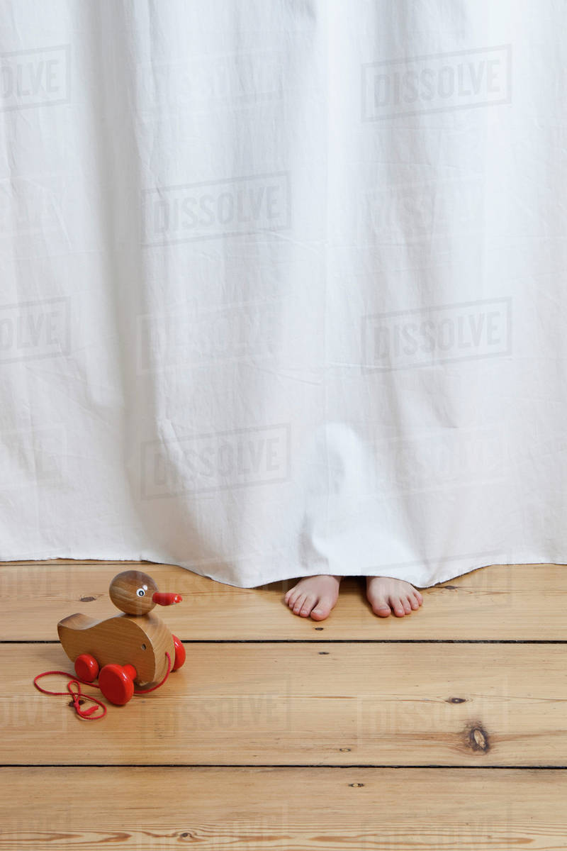 A hiding child's feet sticking out from under a hanging sheet - Stock ...