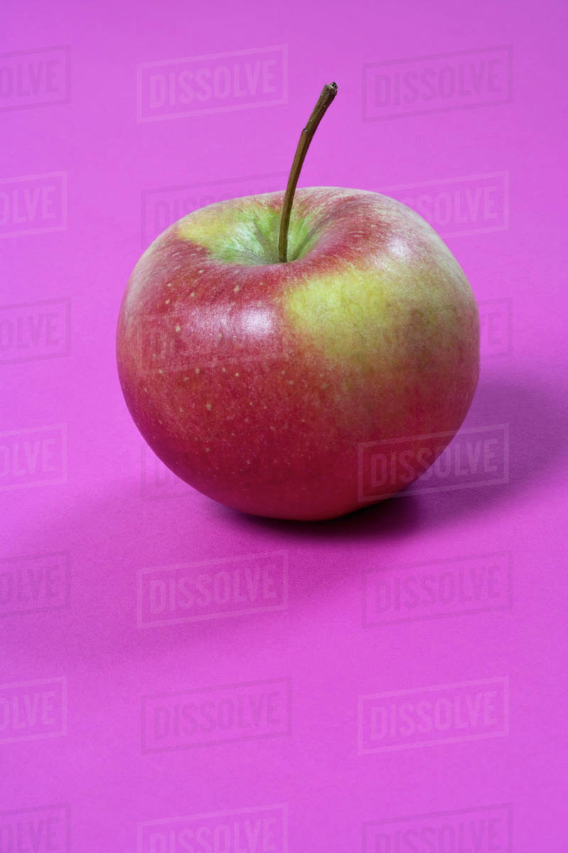 A red apple on a pink background - Stock Photo - Dissolve