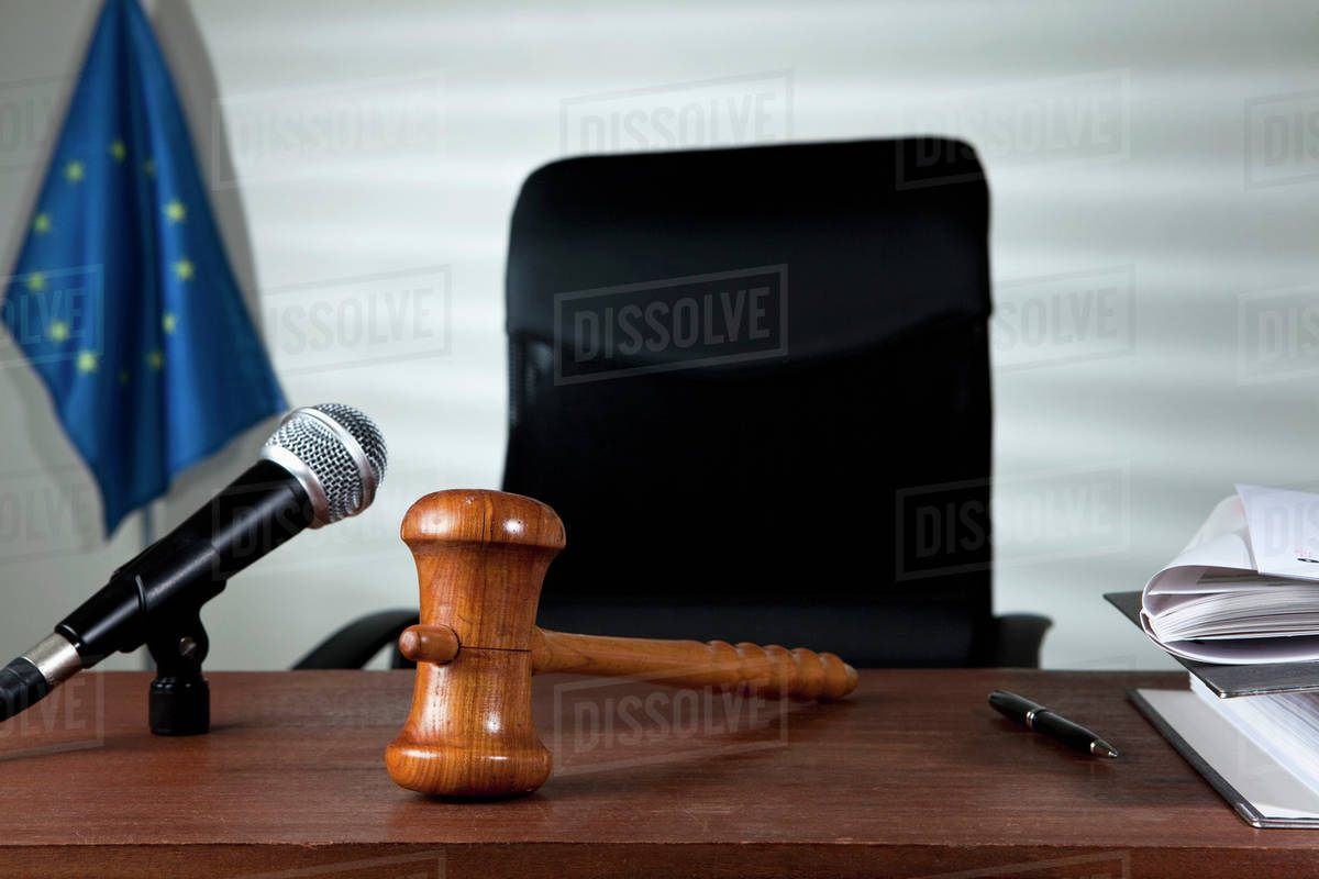 A gavel on a judge's desk in an empty courtroom - Stock Photo - Dissolve