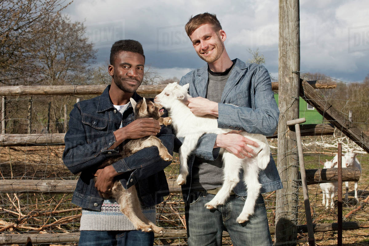 Two male friends holding kid goats - Royalty-free Stock Photo | Dissolve