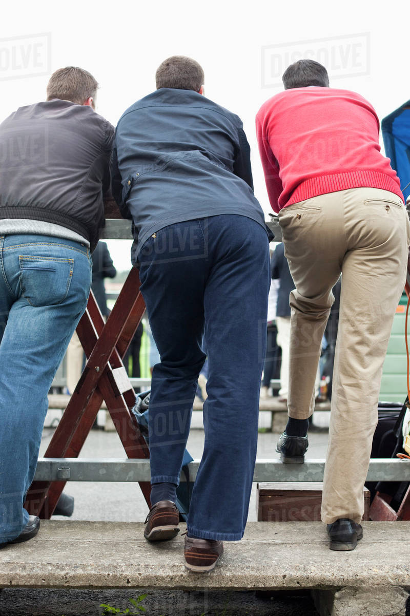 Rear view of three male spectators at a horse racing track - Royalty ...