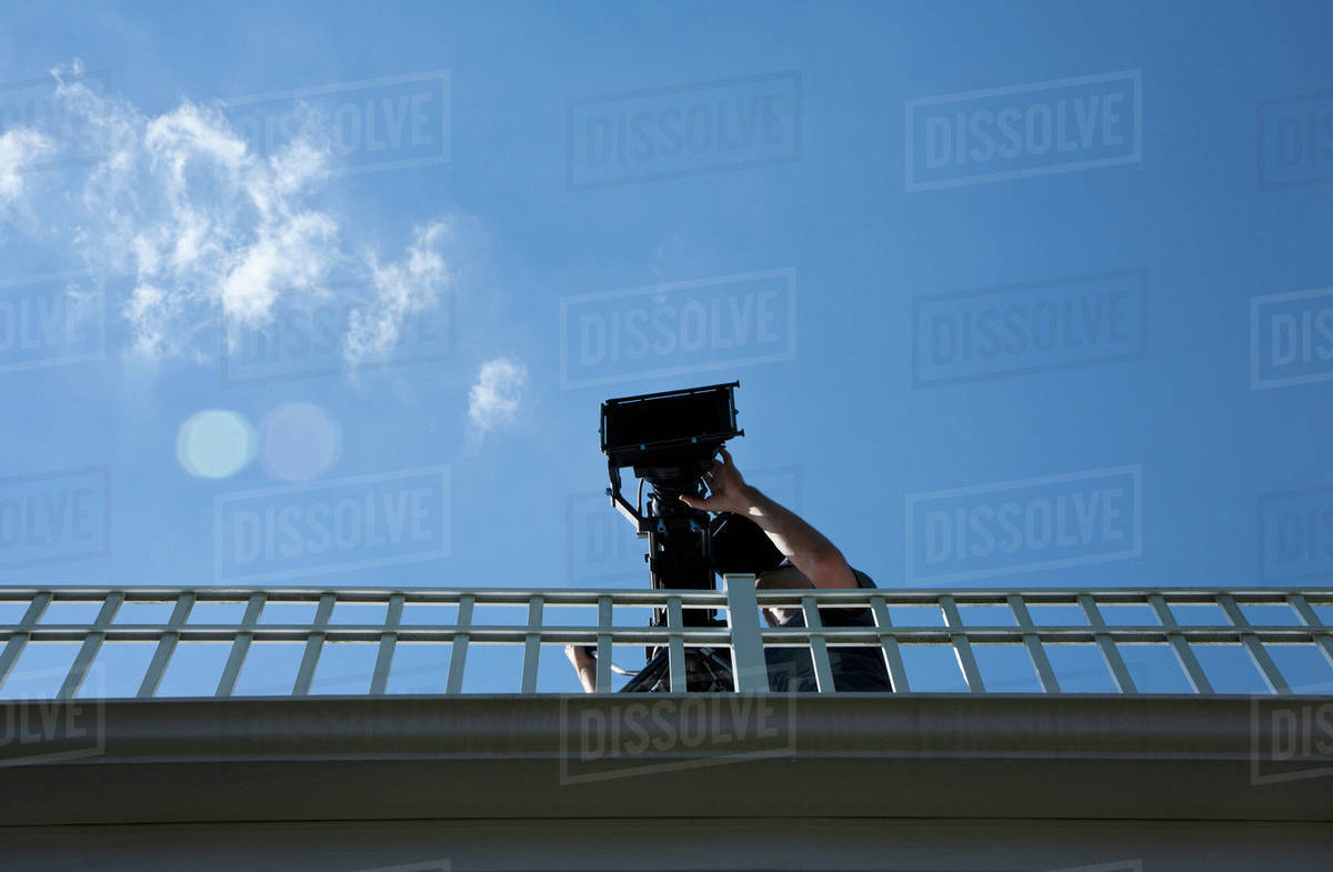 A cameraman filming on a pedestrian bridge, low angle view - Royalty ...