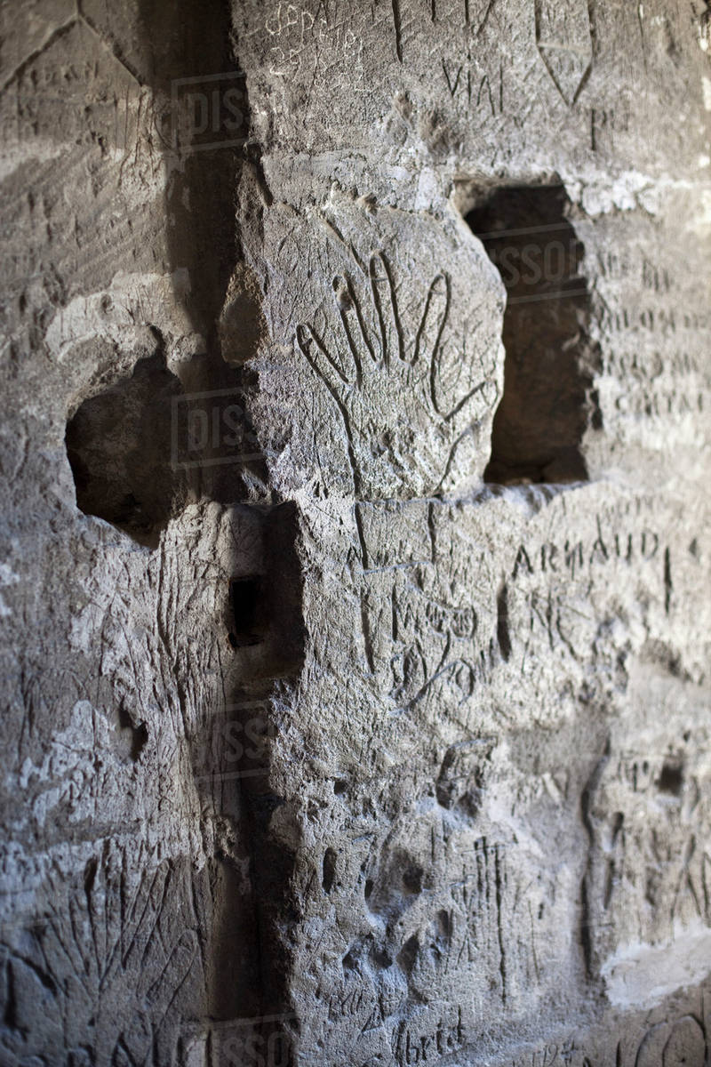 Handprints and handwritten graffiti etched into a stone wall - Royalty ...