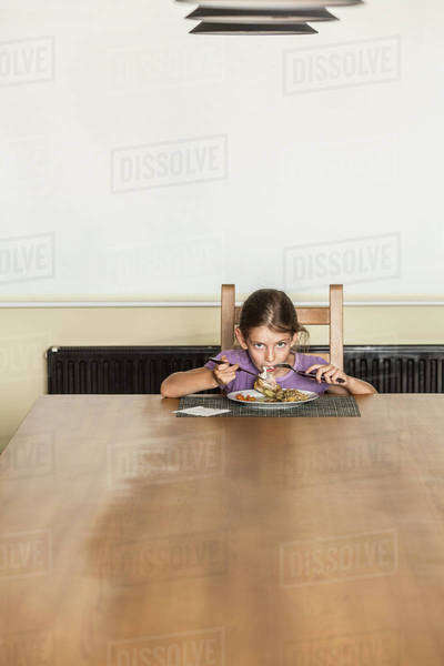 Portrait of girl eating food at dining table in house - Royalty-free ...