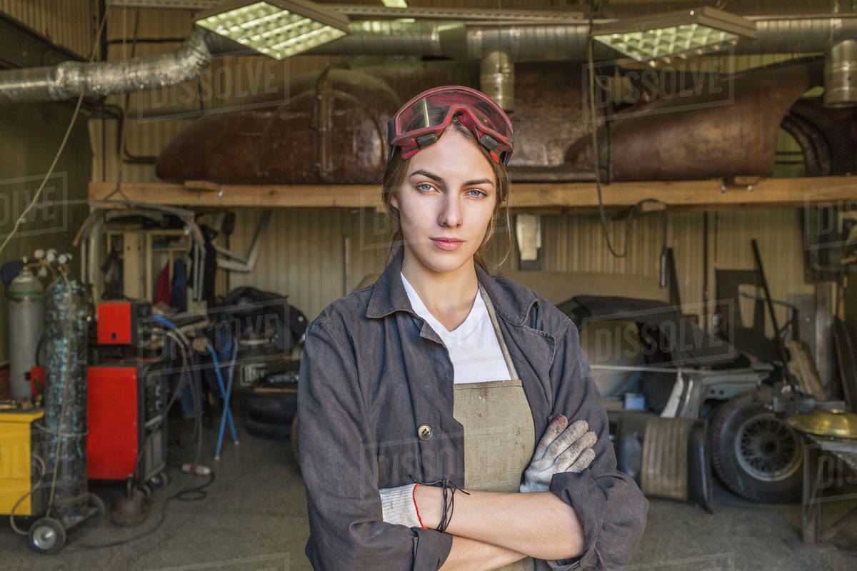 Portrait of confident female mechanic with arms crossed at garage ...