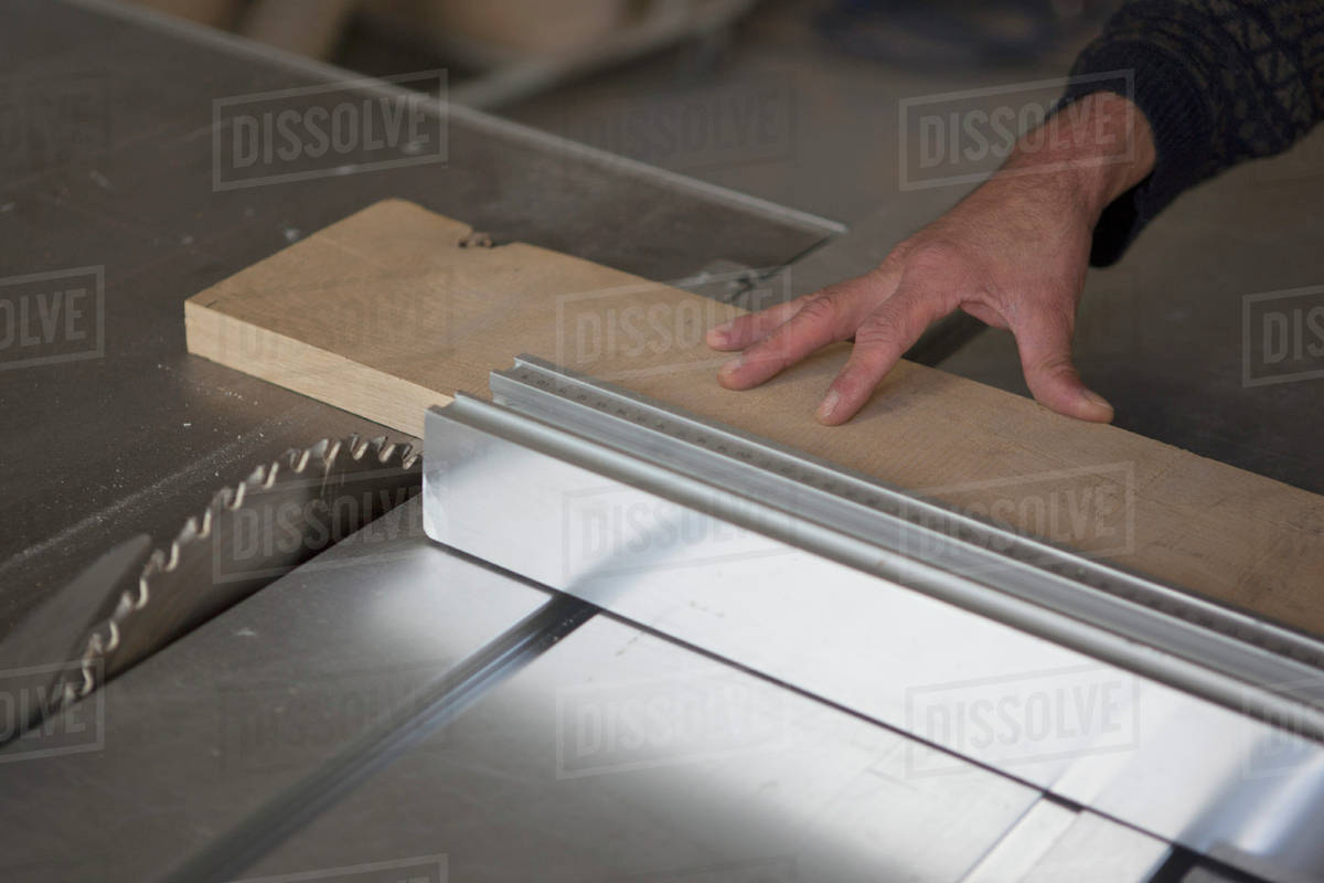 Cropped image of carpenter using sliding table saw in workshop ...