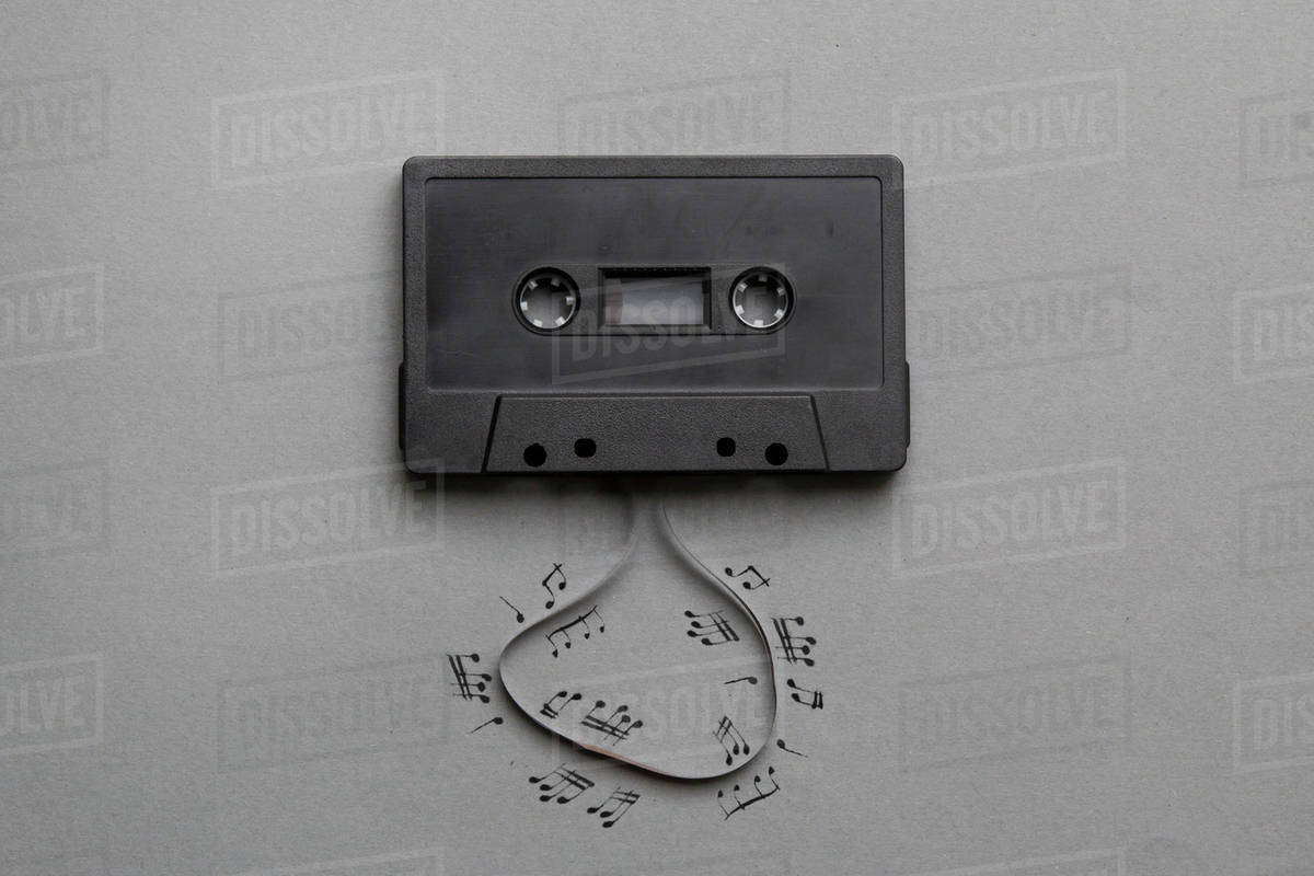 High angle view of music notes drawn around cassette reel on gray ...