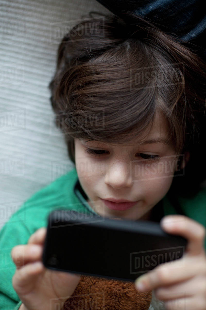 Boy playing with mobile phone - Stock Photo - Dissolve