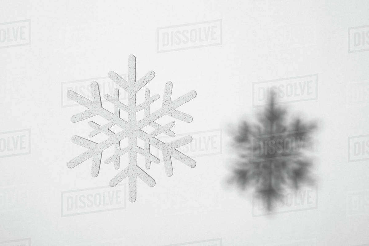 Close-up of snowflake and its shadow against white background - Royalty ...