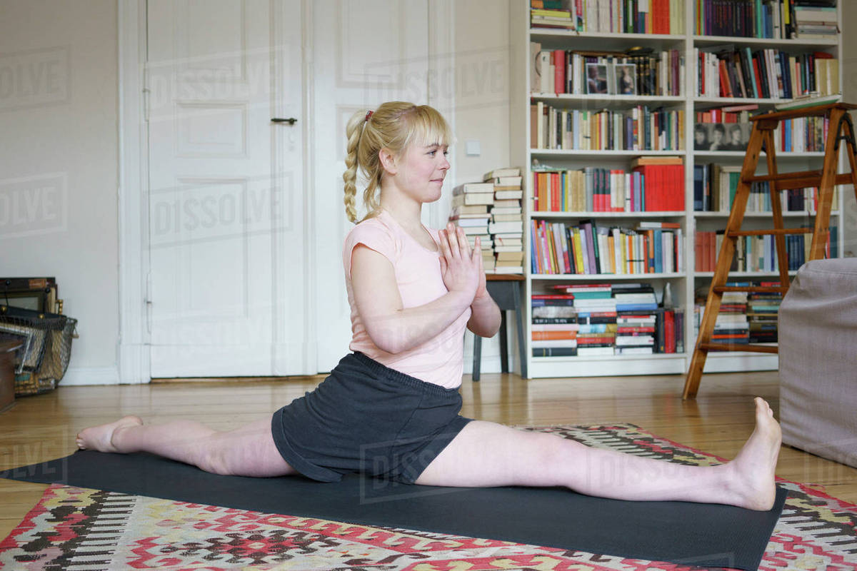 Flexible woman doing splits while exercising in living room at home ...