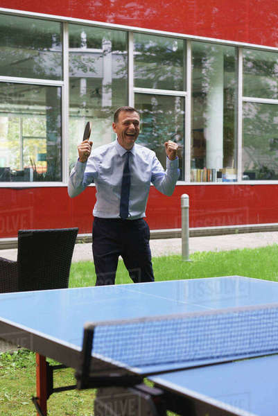 Happy businessman enjoying while playing table tennis at creative ...