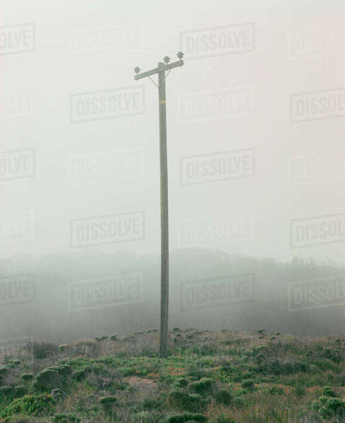 Electricity pylon on hill in foggy weather - Stock Photo - Dissolve