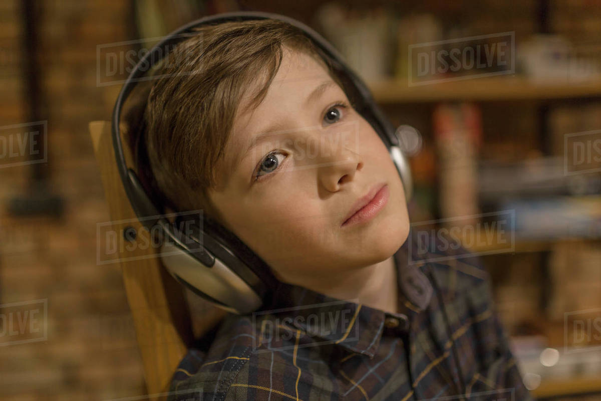 Thoughtful boy listening music through headphones at home - Royalty ...