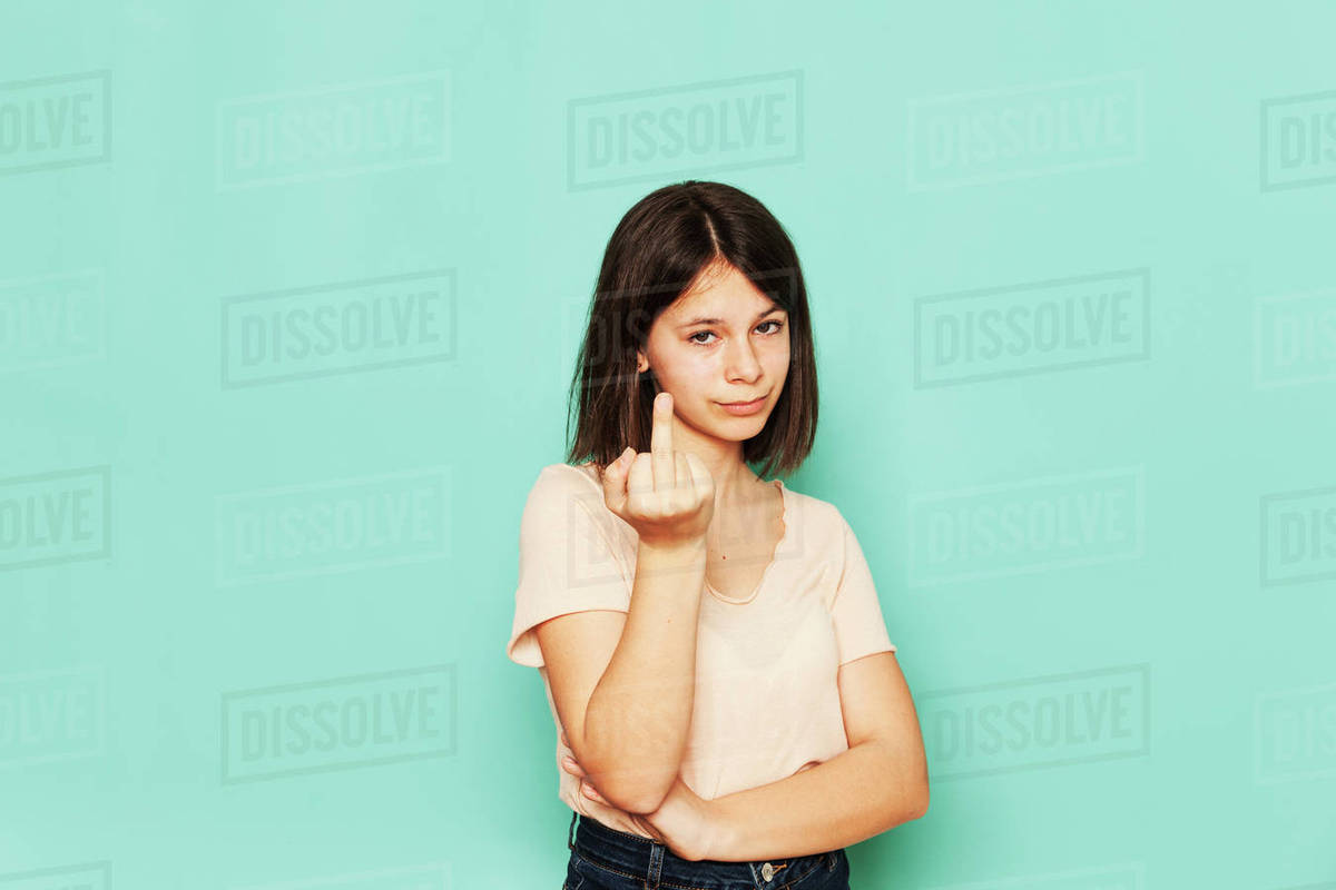 Portrait of rude girl showing middle finger against turquoise ...