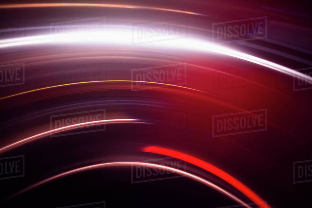 Abstract image of vibrant red light trails against black background ...