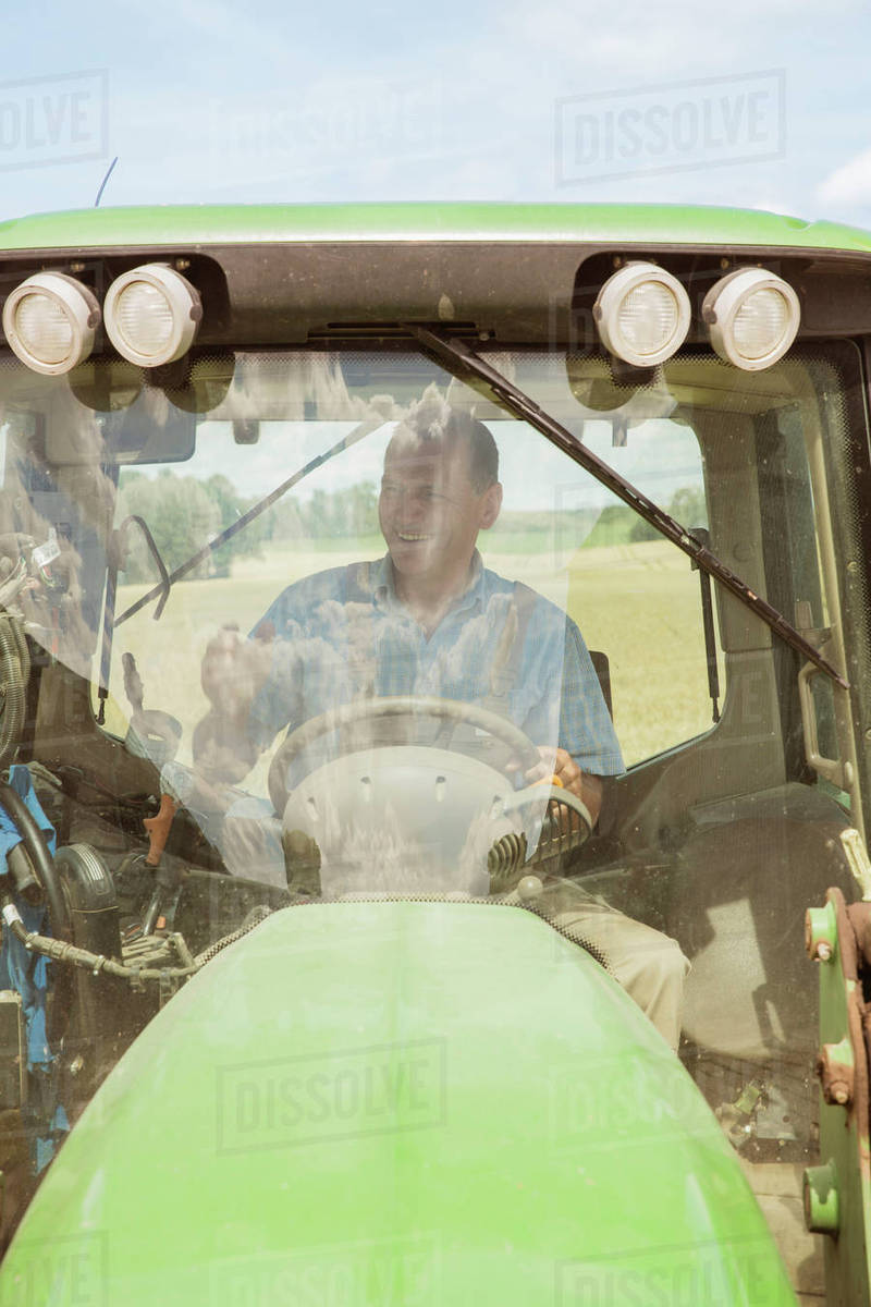 Smiling farmer driving tractor at farm on sunny day - Royalty-free ...