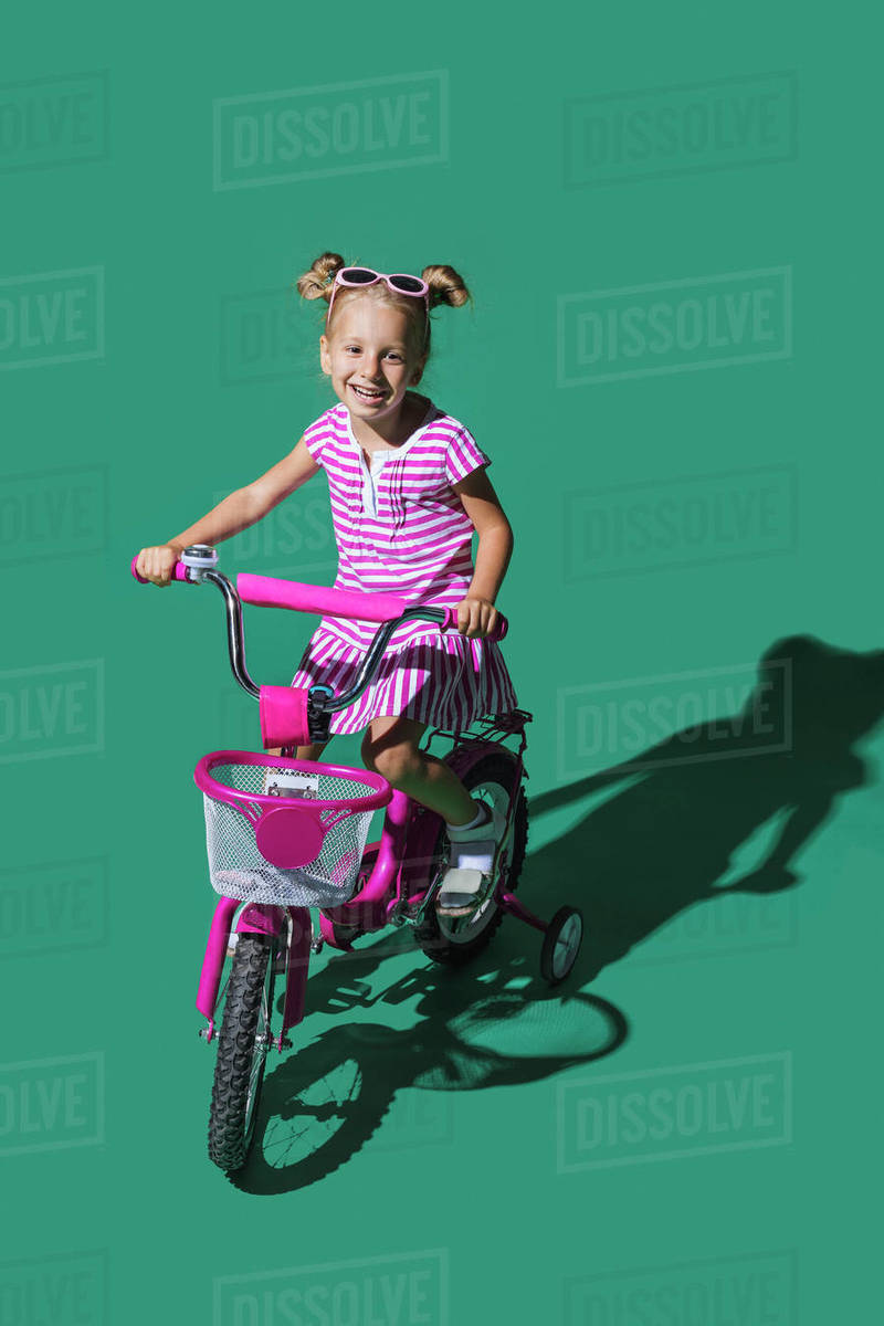 Portrait smiling girl bike riding against green background - Stock ...