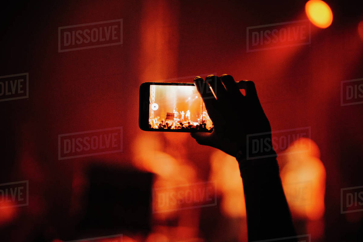 Hand of man in audience video recording concert with camera phone ...