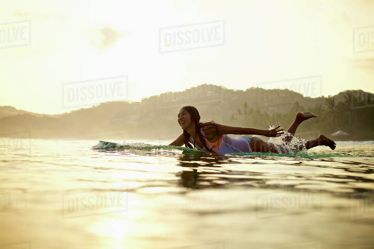 Happy female surfer paddling out in ocean on surfboard, Sayulita ...