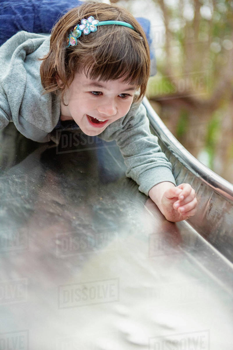 Portrait happy girl going down slide head first - Royalty-free Stock ...
