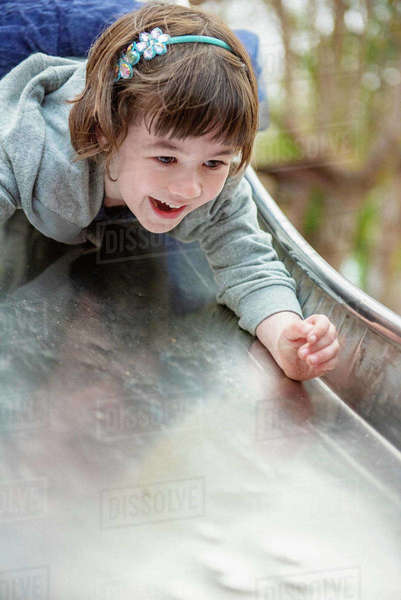Portrait happy girl going down slide head first - Royalty-free Stock ...