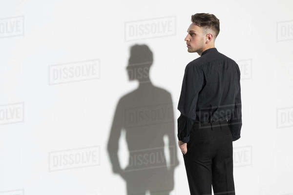 Man and shadow at white wall - Royalty-free Stock Photo | Dissolve