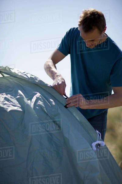 Portrait of young man standing and erecting tent - Royalty-free Stock ...