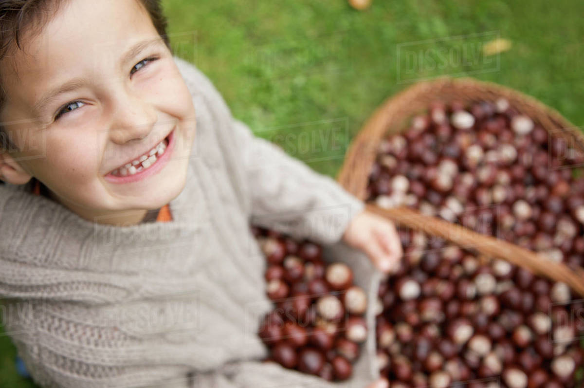 Smiling young boy holding chestnuts - Royalty-free Stock Photo | Dissolve