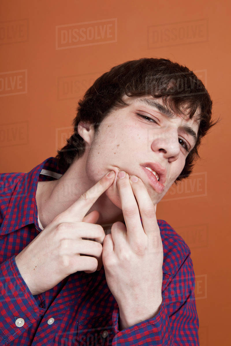 A teenage boy popping a zit on his face, portrait, studio shot - Stock ...