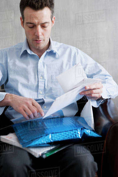 A man sifting through a pile of mail - Royalty-free Stock Photo | Dissolve